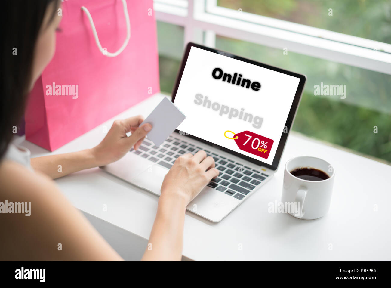 Young woman holding credit card and using laptop computer in cafe ...