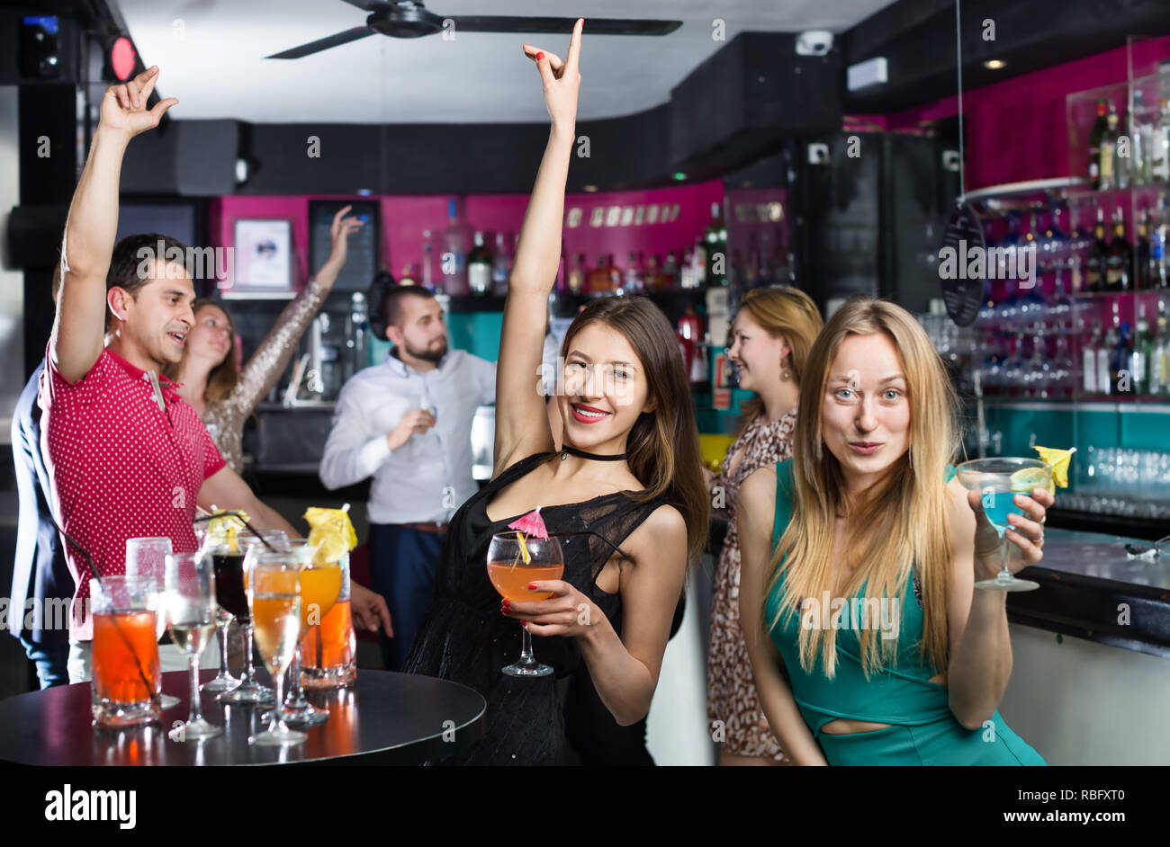 Young cheerful students dancing on party with cocktails at the club ...