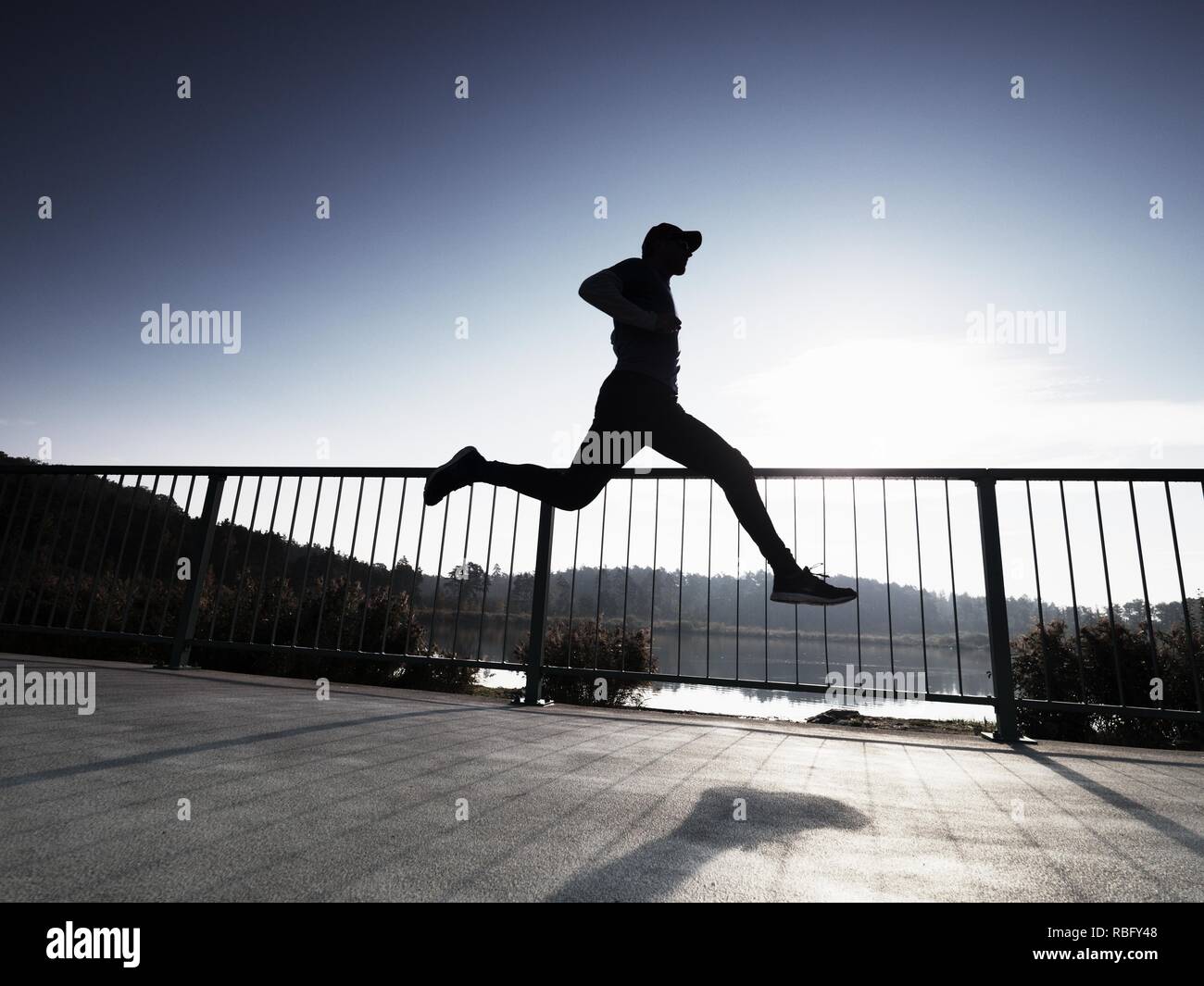 Full section view of fit slim man running on boardwalk. He is in sports ...