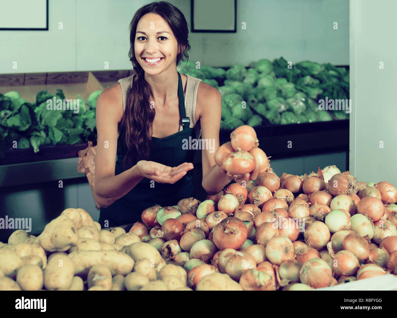 portrait of young smiling russian woman in apron selling unpeeled ...