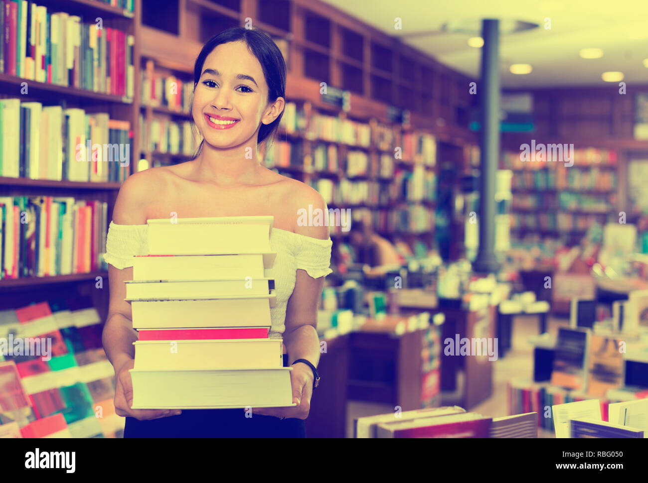 Smiling cheerful positive glad attractive girl holding pile of books ...