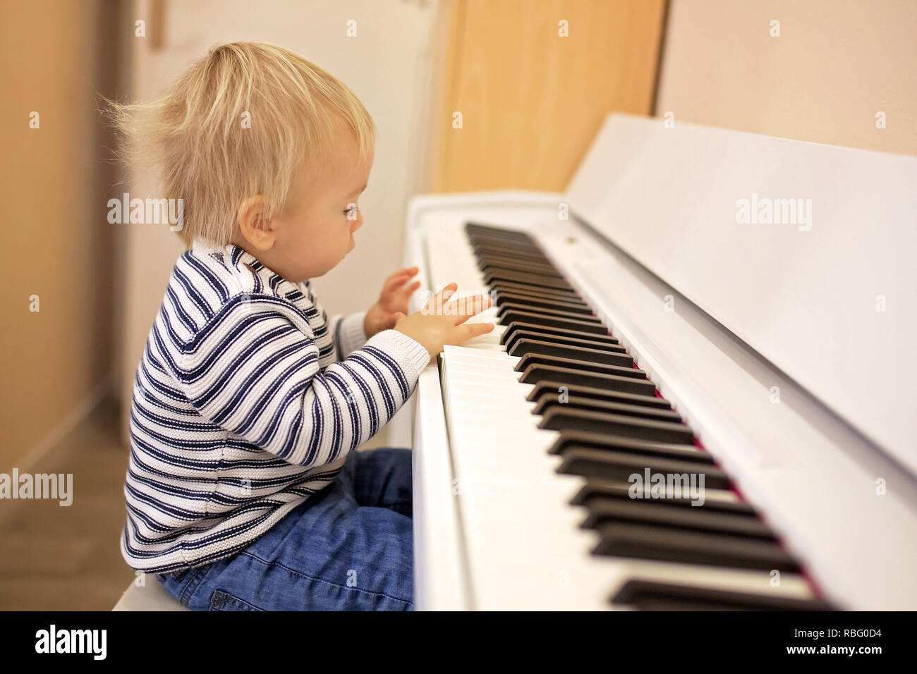 Sweet positive toddler child playing piano. Early music education for ...