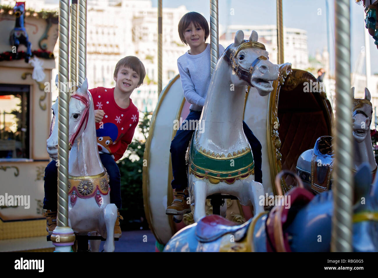 Sweet boys, brothers, riding in a Santa Claus sledge on a merry-go ...