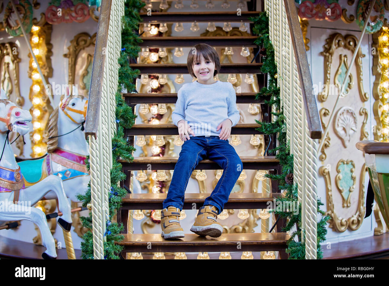 Sweet boys, brothers, riding in a Santa Claus sledge on a merry-go ...