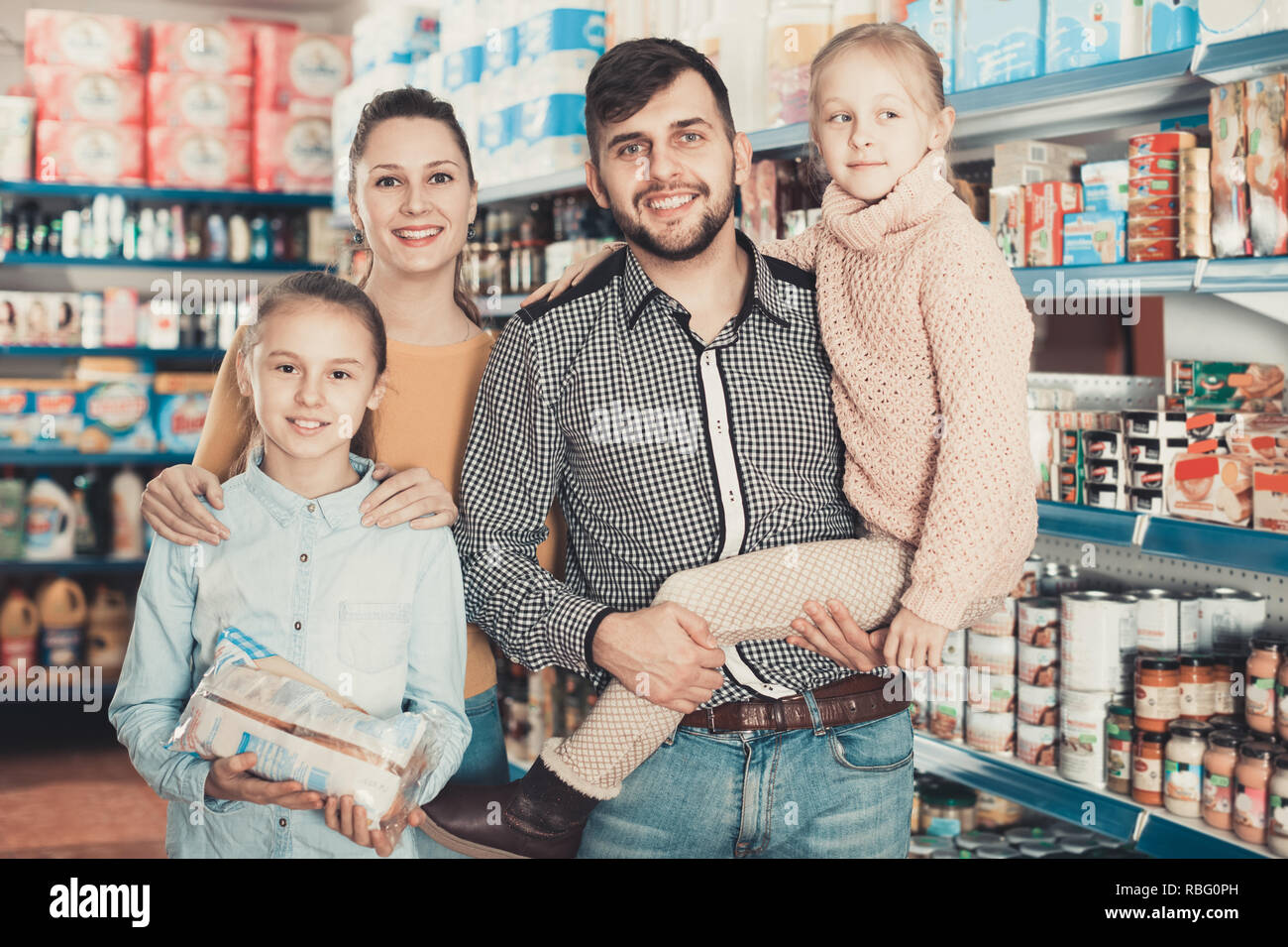 Happy parents with two little girls during family shopping in grocery ...