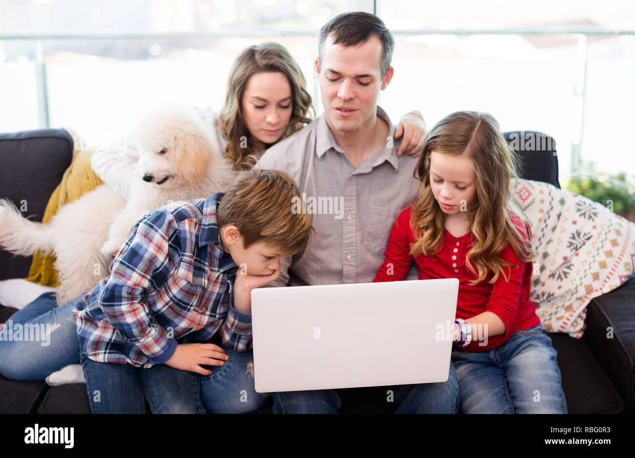 Parents with children enjoying movie on laptop together at home Stock ...