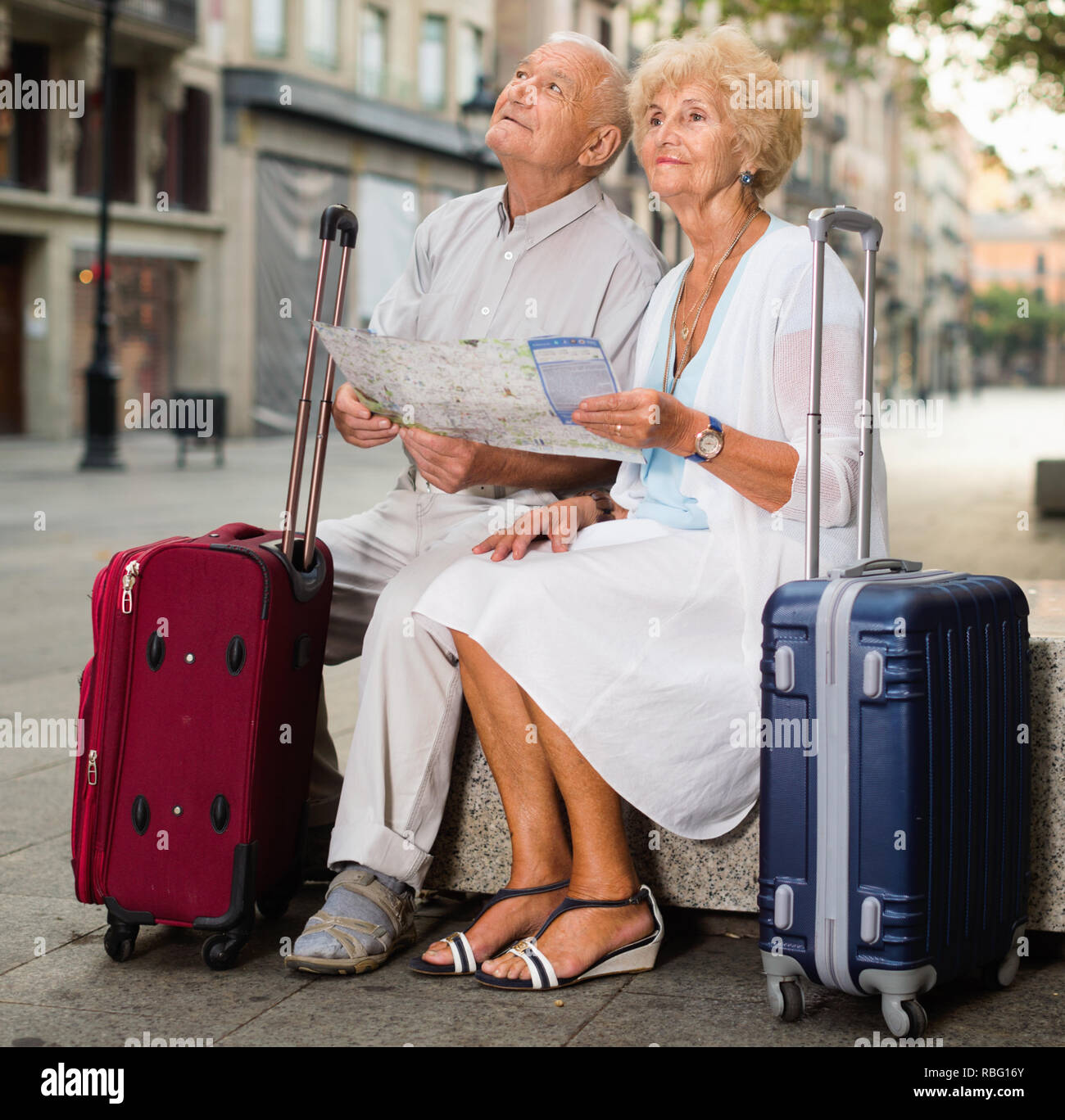 Traveling glad cheerful smiling mature spouses resting on stone bench ...