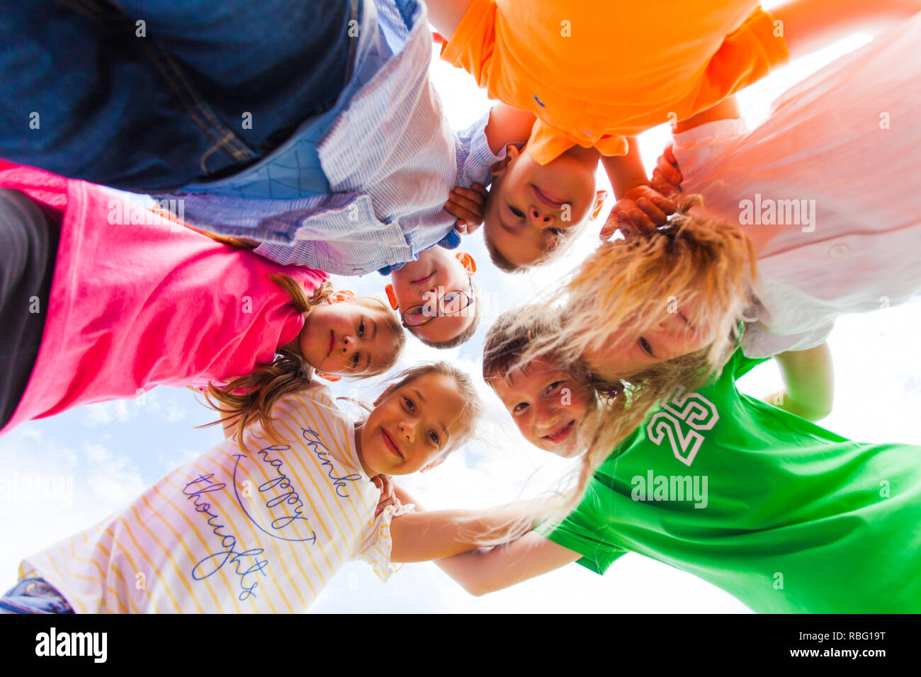 A huddle of school kids in colorful t-shirt standing shoulder to ...