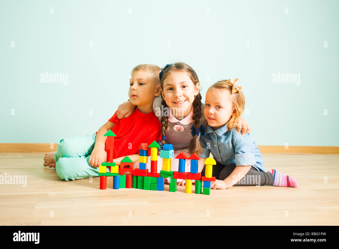 Happy smiling siblings sitting on a floor embracing looking at the ...