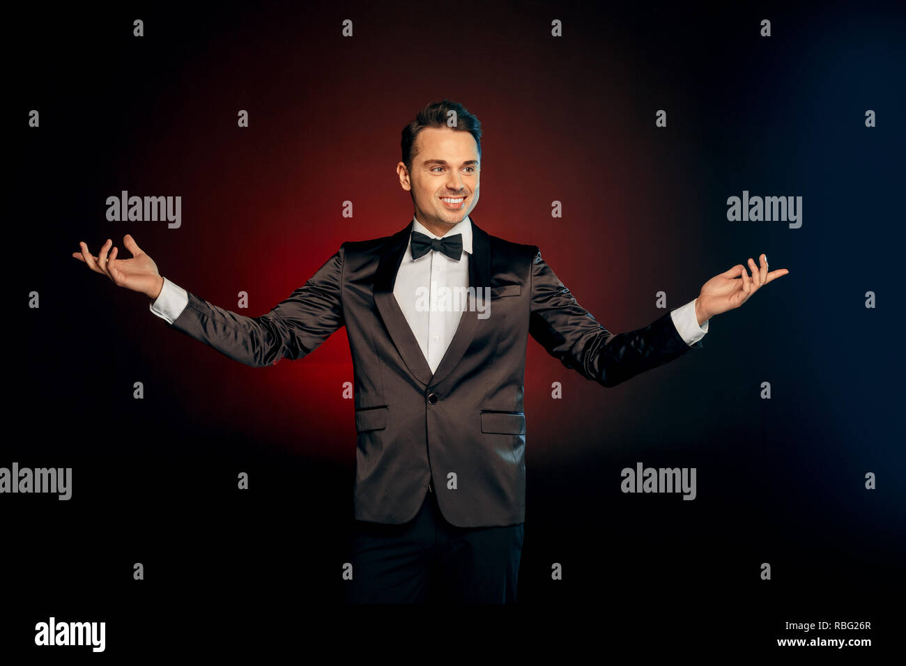 Professional showman wearing suit standing isolated on black and red ...