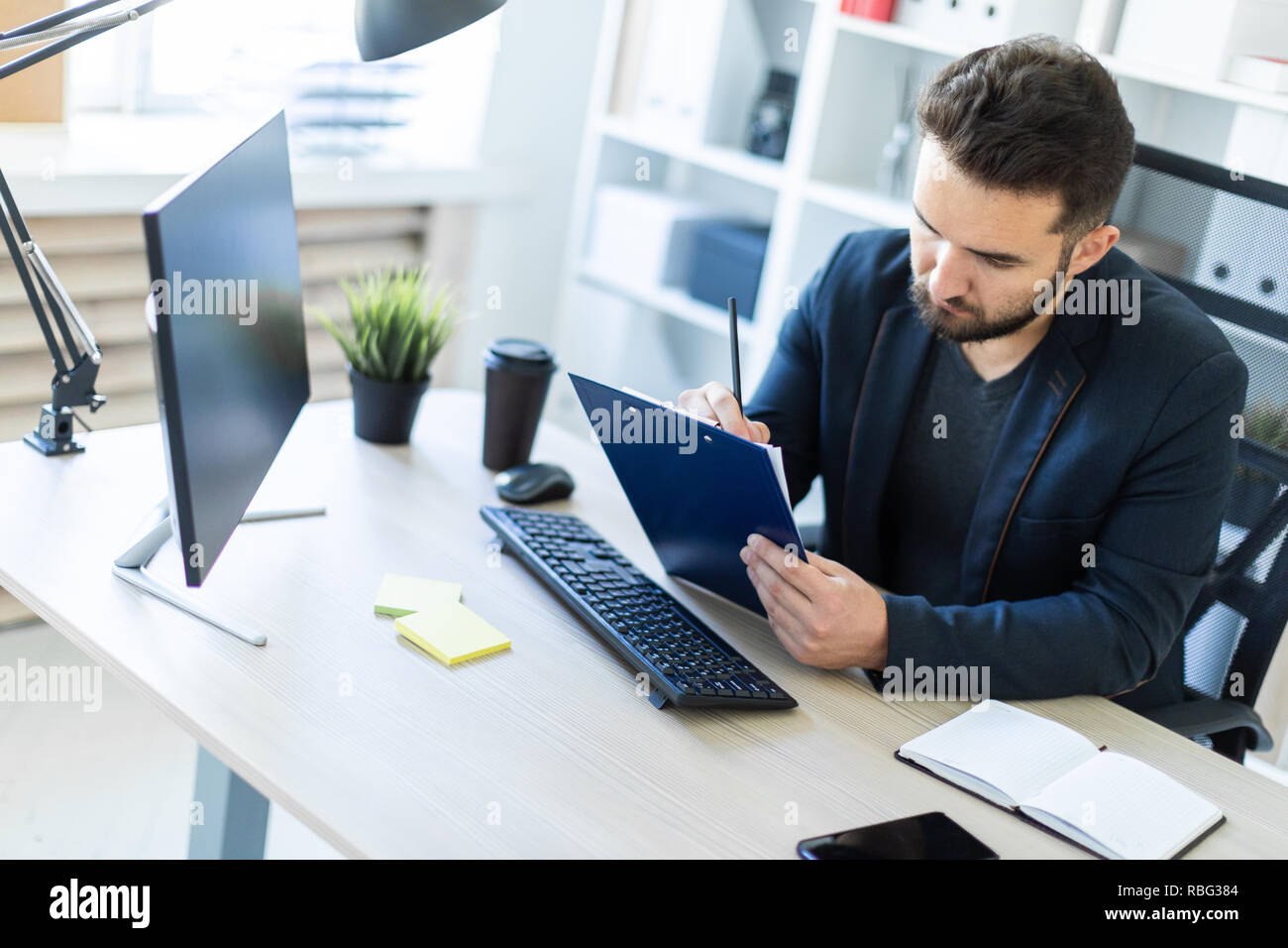 The young man works in the office at a computer Desk with documents ...