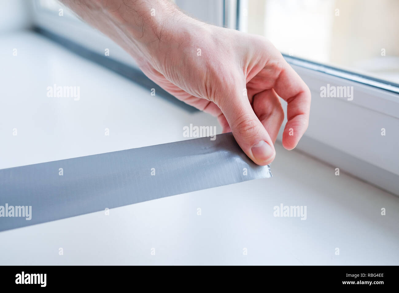 Worker putting sealing tape on window in house Stock Photo - Alamy