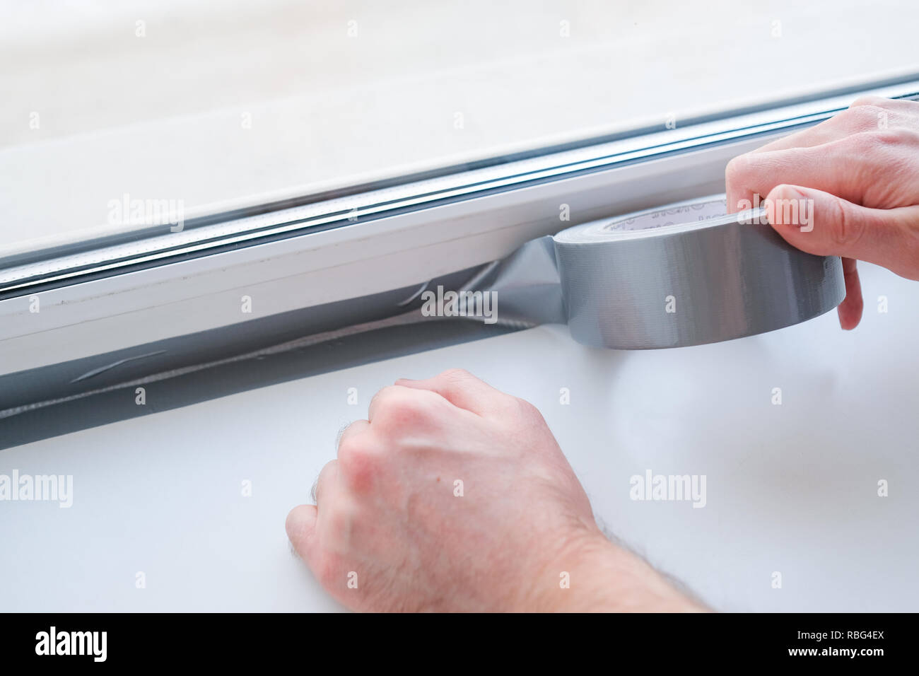 Worker putting sealing tape on window in house Stock Photo - Alamy