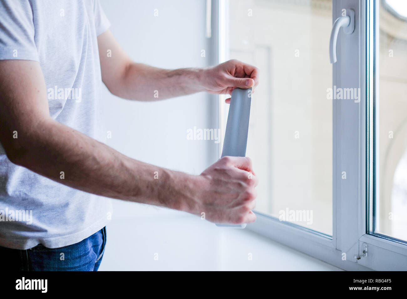 Worker putting sealing tape on window in house Stock Photo - Alamy