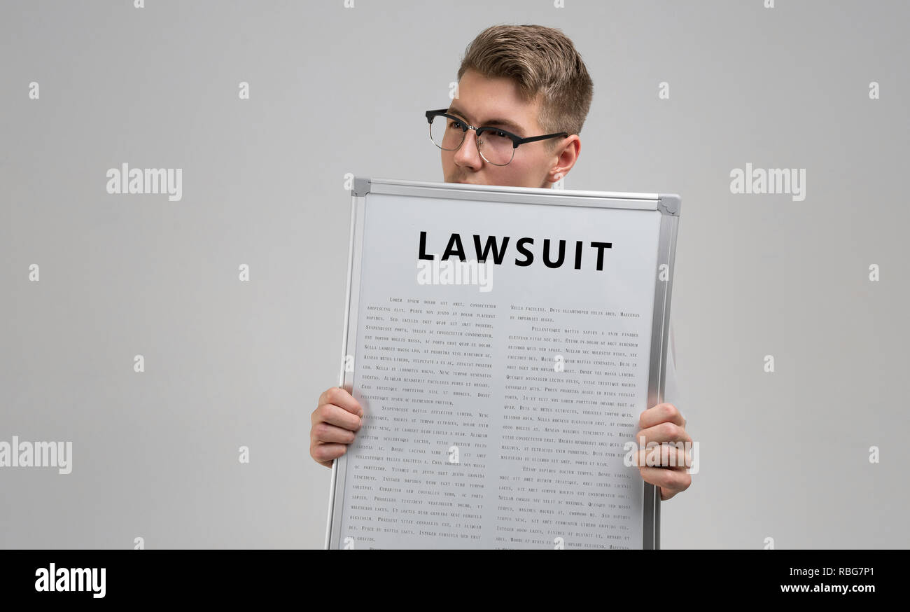 young man keeps in front of him a poster with the inscription lawsuit ...