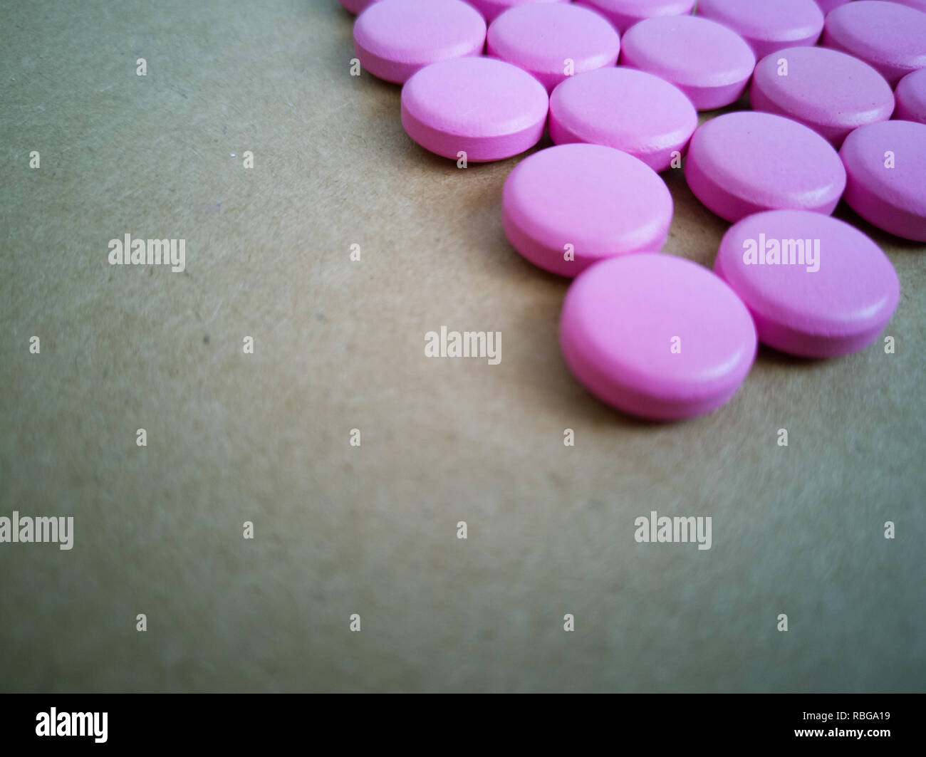 pink pills laid out in shape of a heart on brown background. coloured ...