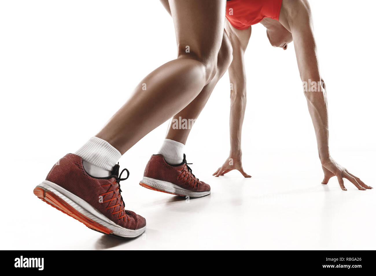Portrait of young sporty woman at starting block of race isolated over ...