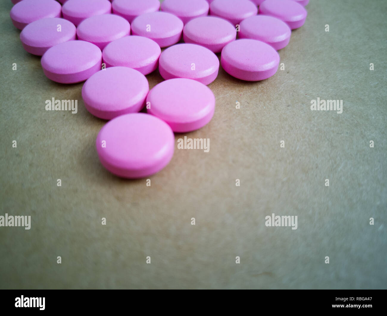pink pills laid out in shape of a heart on brown background. coloured ...
