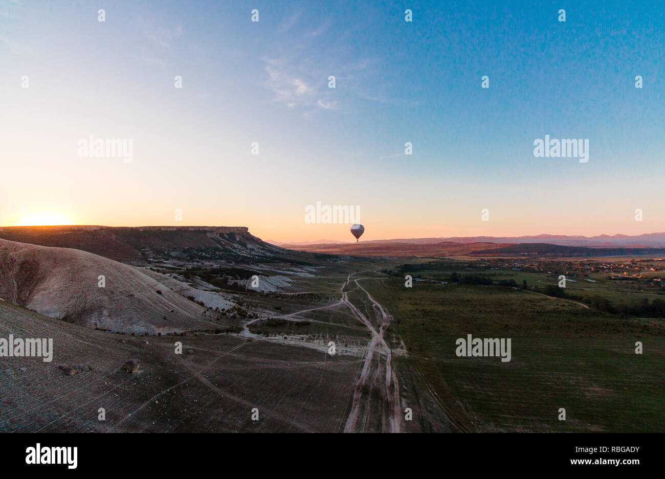 Hot air balloon shadow on the ground during sunrise flying over the ...