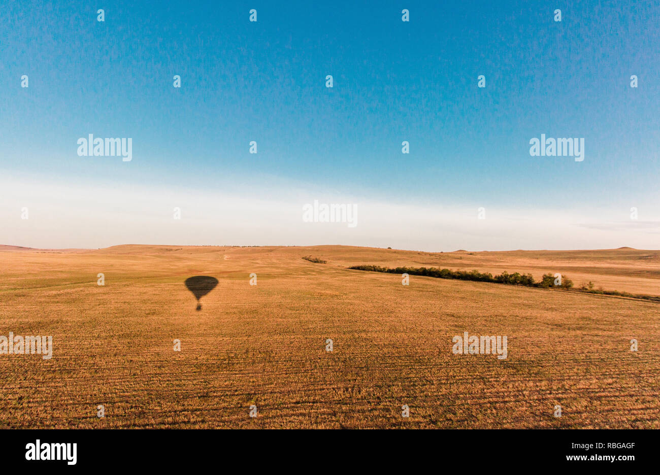 Hot air balloon shadow on the ground during sunrise flying over the ...