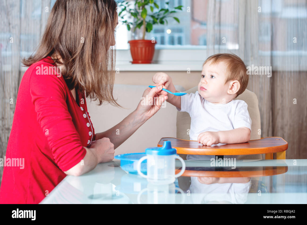 Mom feeding the baby holding out her hand with a spoon of food in the ...