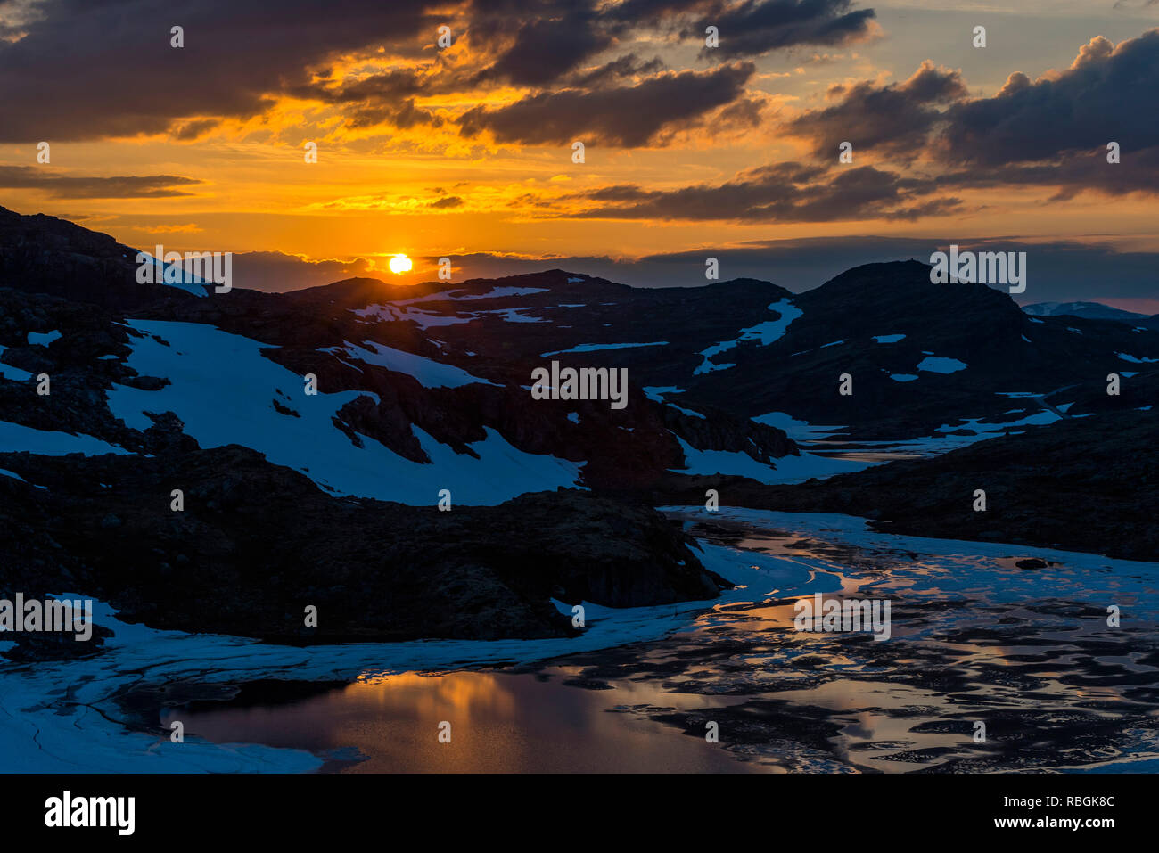 The spring sunset setting the mountain landscape with a melting lake in ...