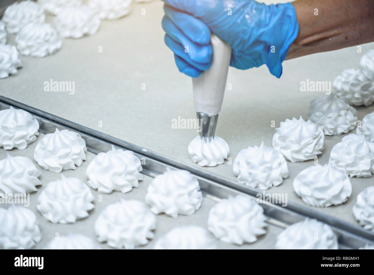 The process of making meringue and desserts. A gloved hand squeezes the ...