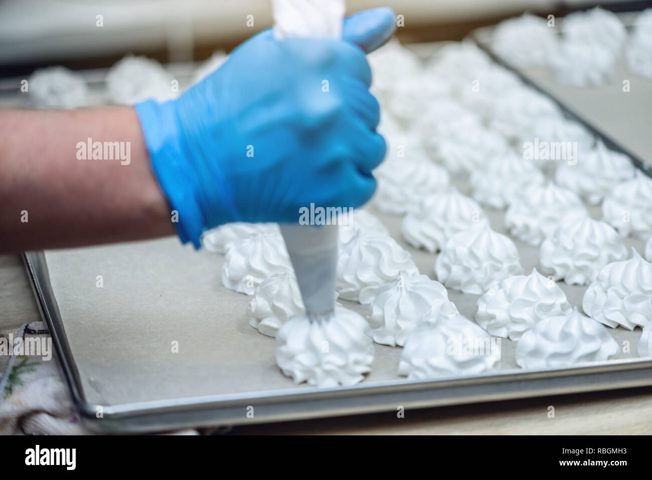 The process of making meringue and desserts. A gloved hand squeezes the ...