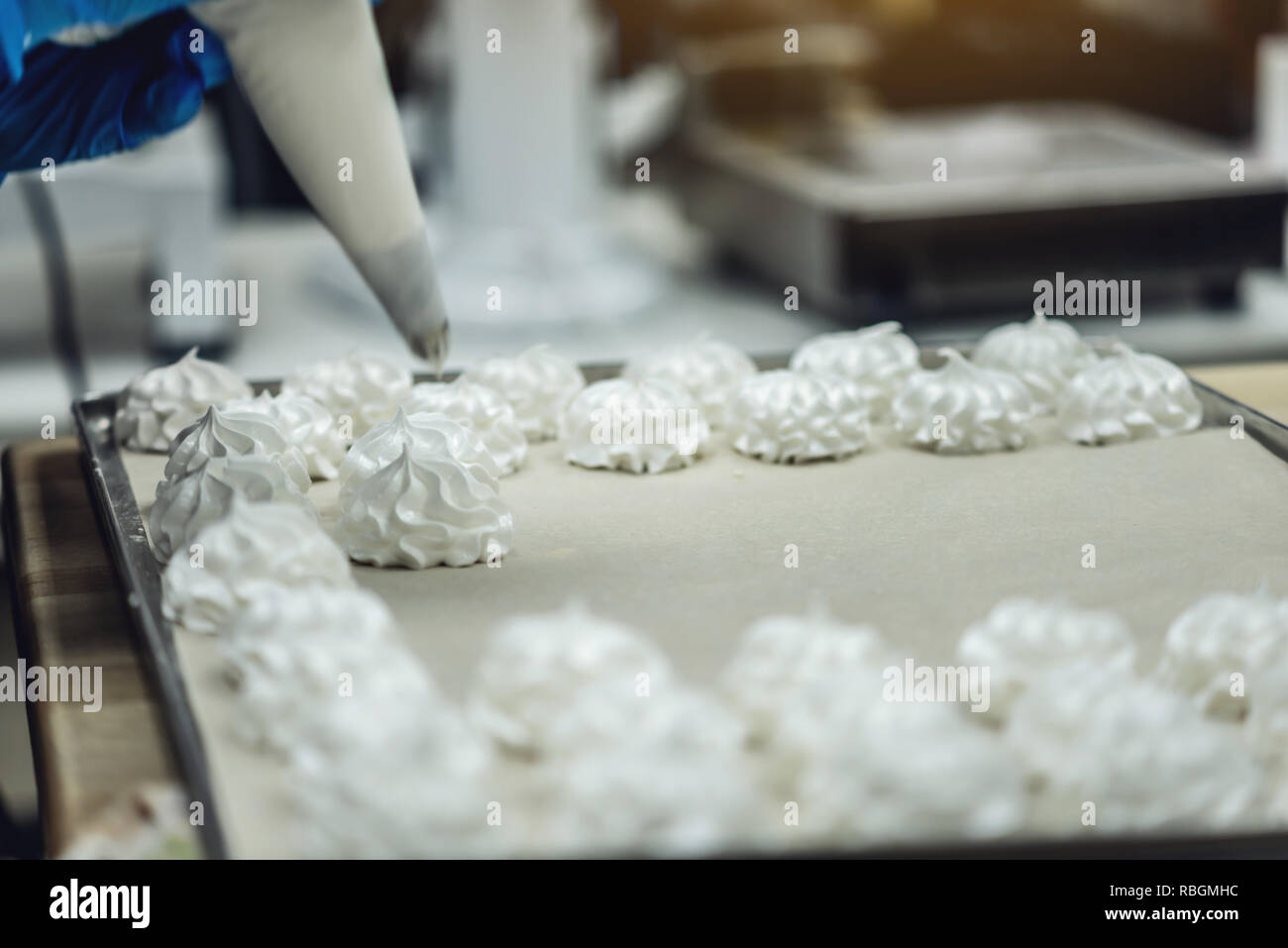 The process of making meringue and desserts. A gloved hand squeezes the ...