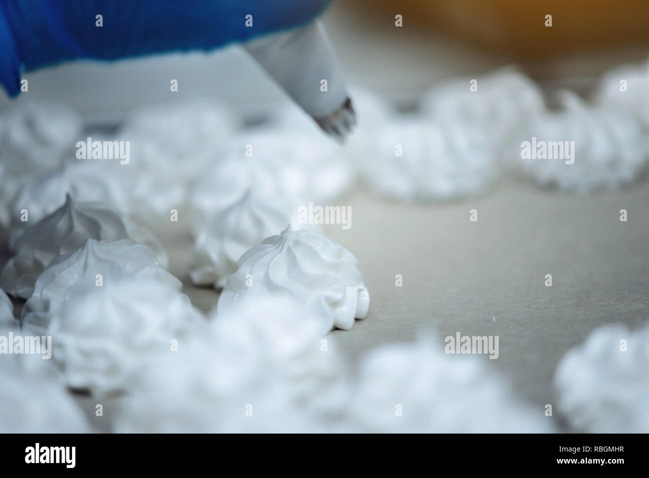 The process of making meringue and desserts. A gloved hand squeezes the ...