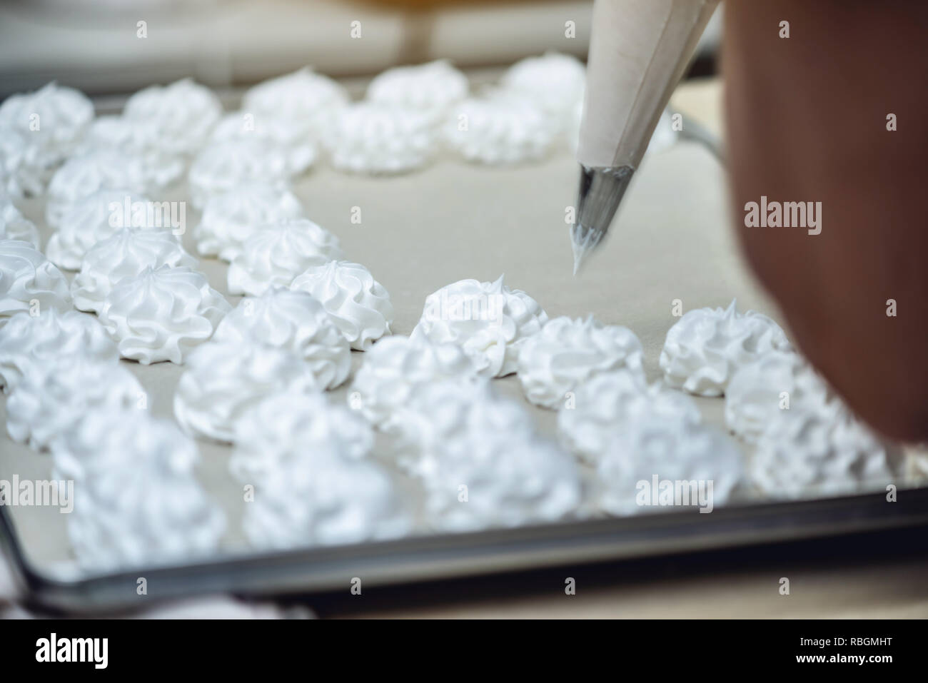 The process of making meringue and desserts. A gloved hand squeezes the ...