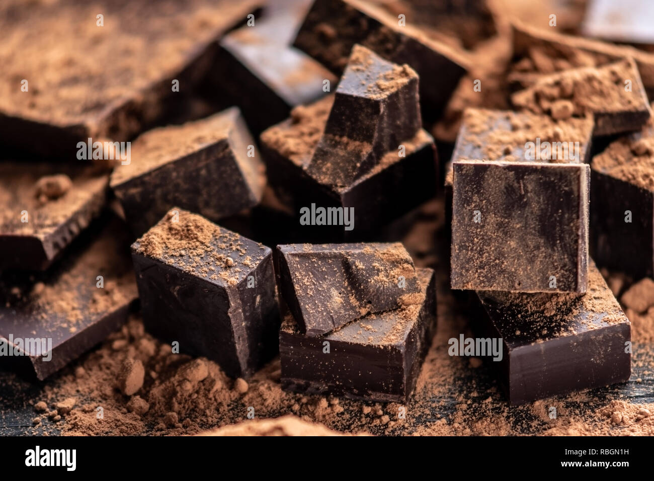 Pieces of dark bitter chocolate with cocoa powder on dark wooden ...