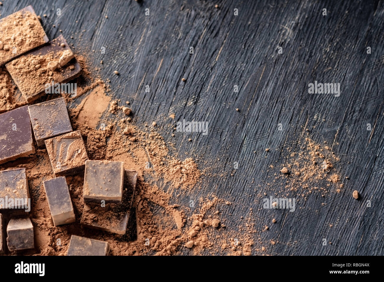 Pieces of dark bitter chocolate with cocoa powder on dark wooden ...