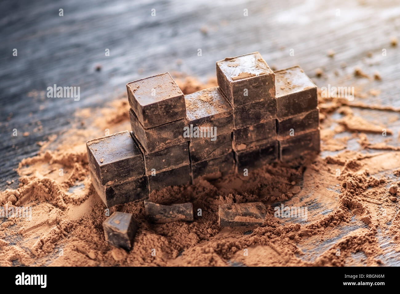 Pieces of dark bitter chocolate with cocoa powder on dark wooden ...