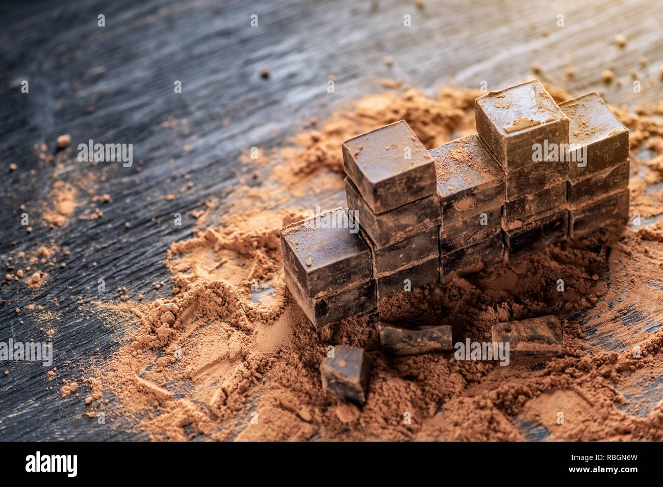 Pieces of dark bitter chocolate with cocoa powder on dark wooden ...