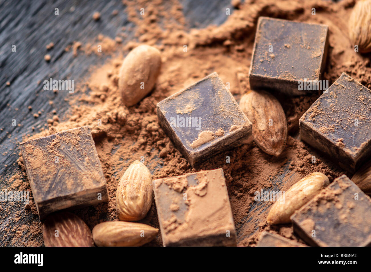 Pieces of dark bitter chocolate with cocoa powder and almonds nuts on ...
