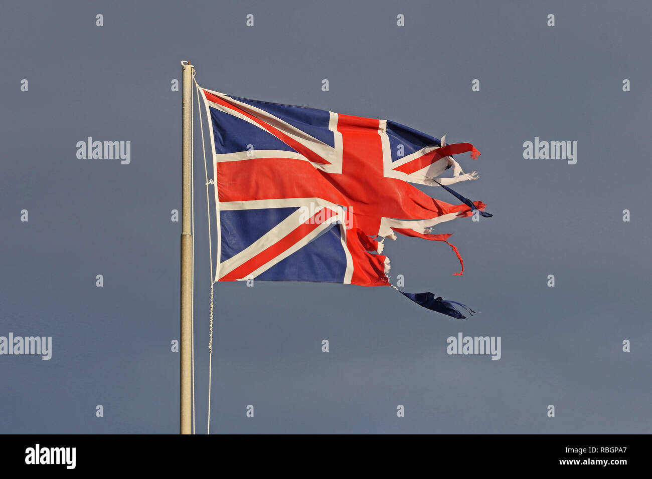 British flag or Union Jack torn and tattered flying in the winter by ...