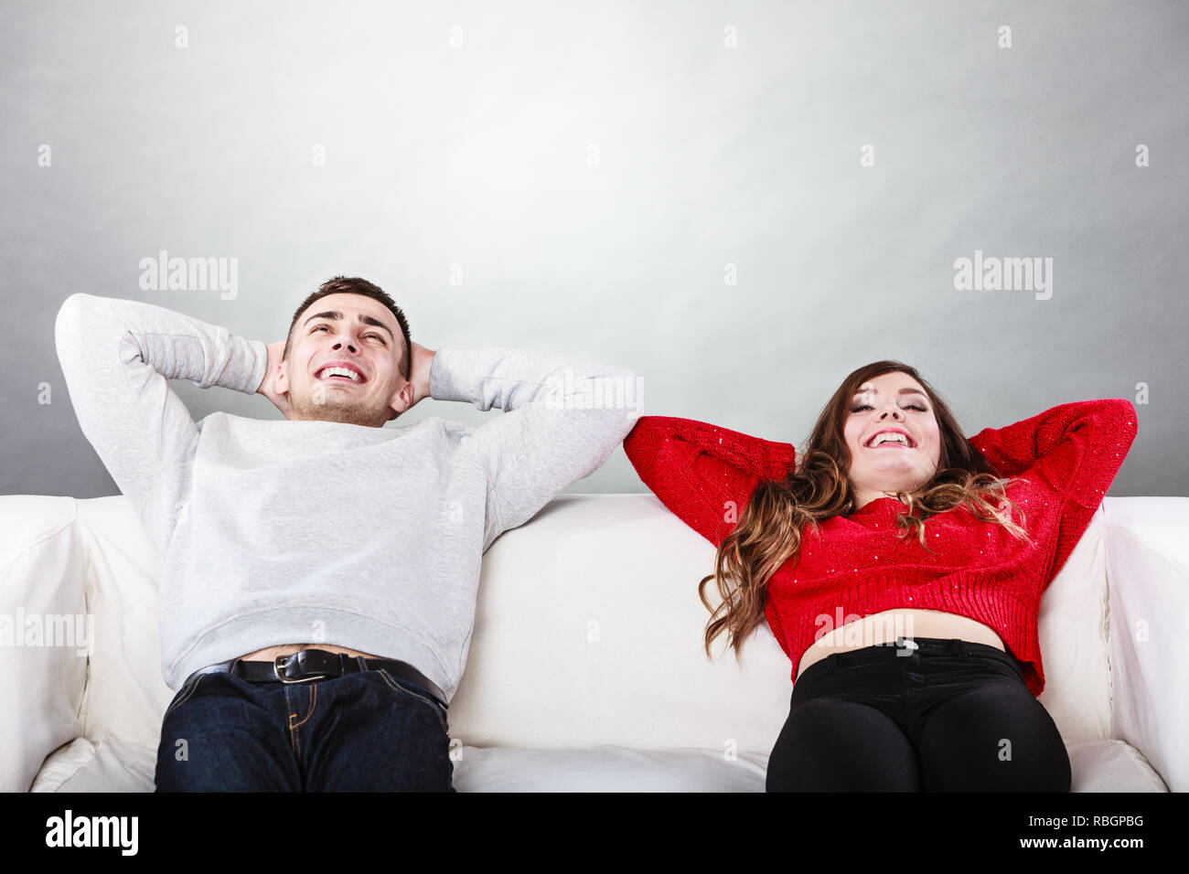Happy, smiling young couple relaxing on couch at home. Calm, carefree ...