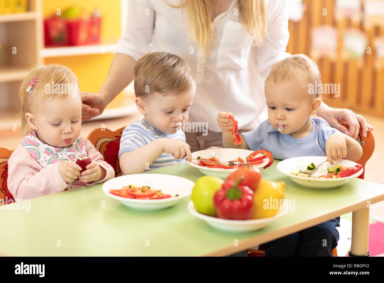 group of kids eating from plates in day care centre Stock Photo - Alamy