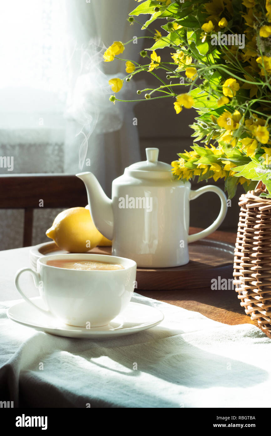 Early morning with cup of tea and fresh wild flowers in basket. Rustic ...