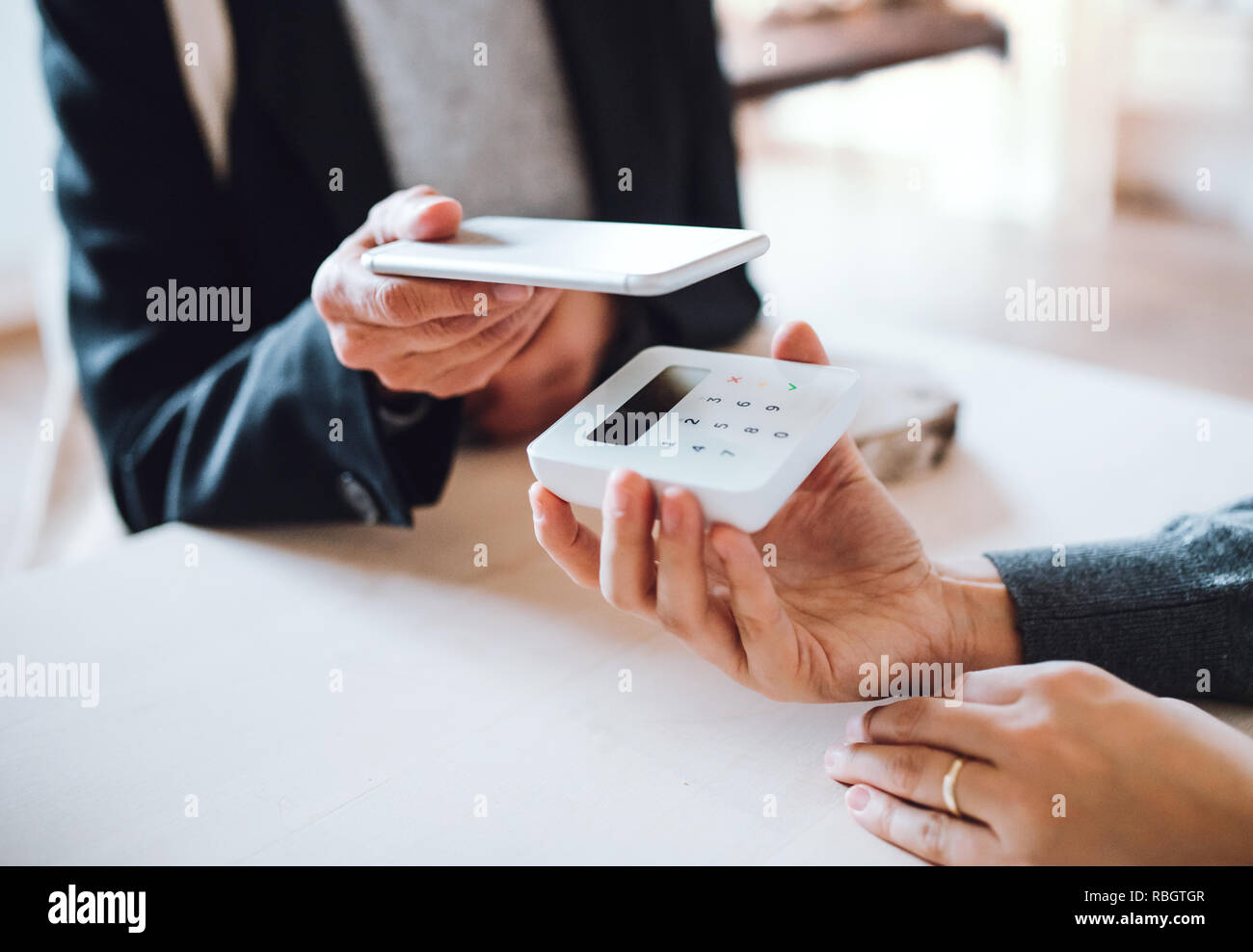 A midsection of customer and shop assistant making mobile payment in a ...