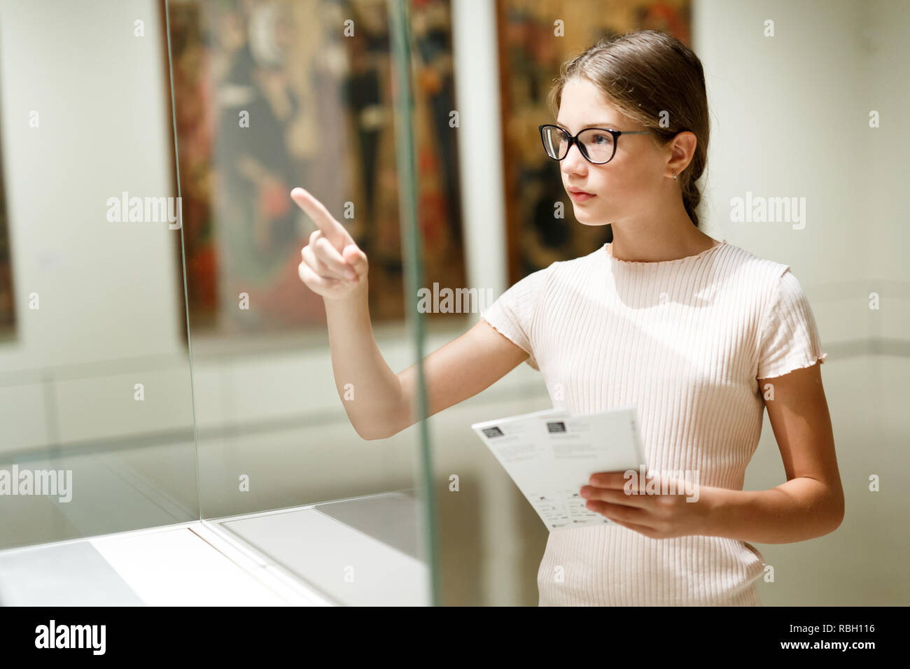 Positive tween girl observing with interest exhibition in art gallery ...