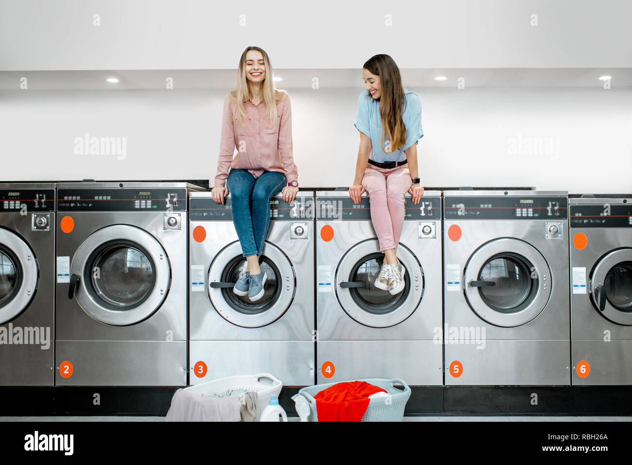 Two Cheerful Girlfriends Waiting For Washing While Sitting On The