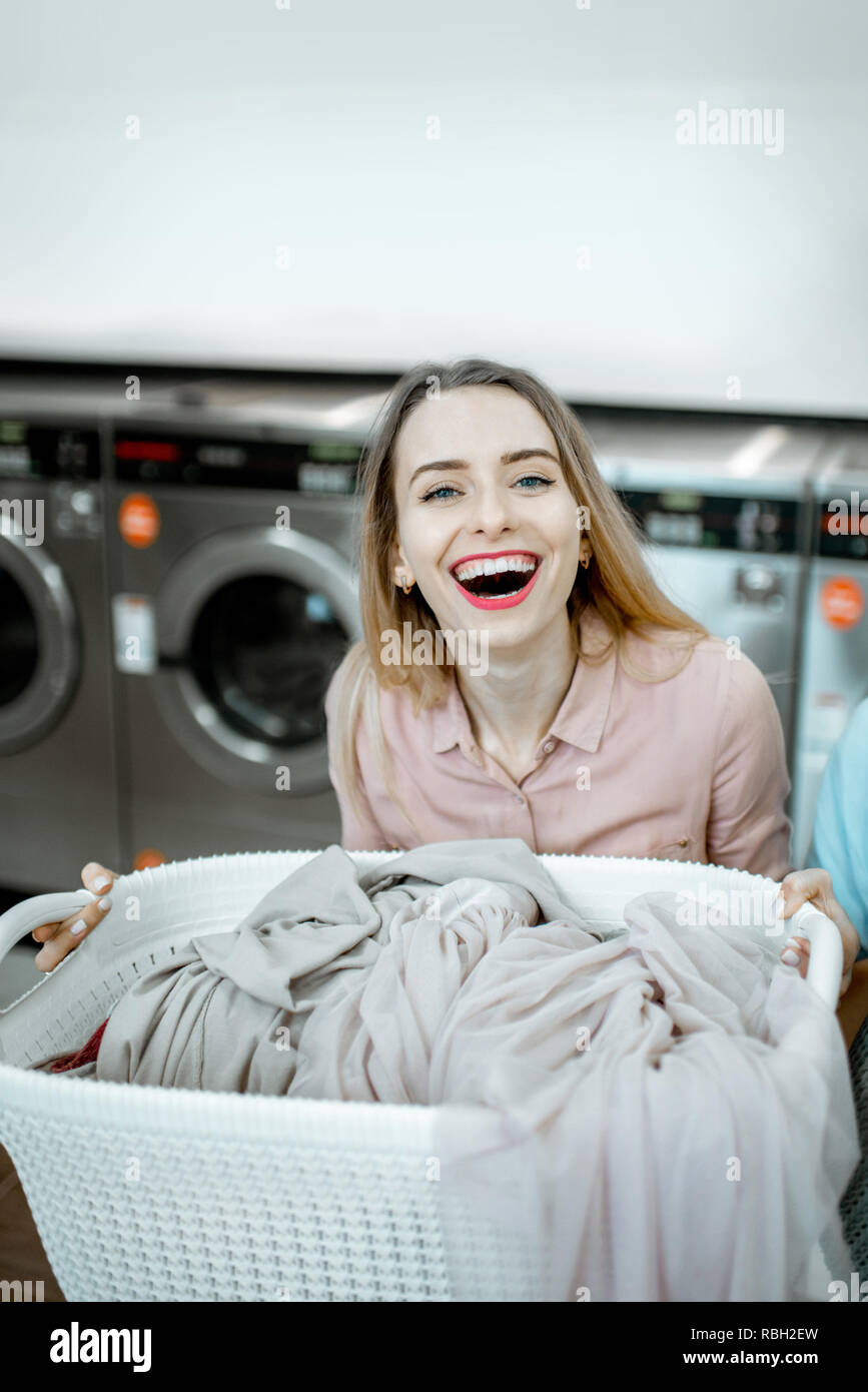 Portrait of a cheerful woman standing with baskets full of clothes for ...