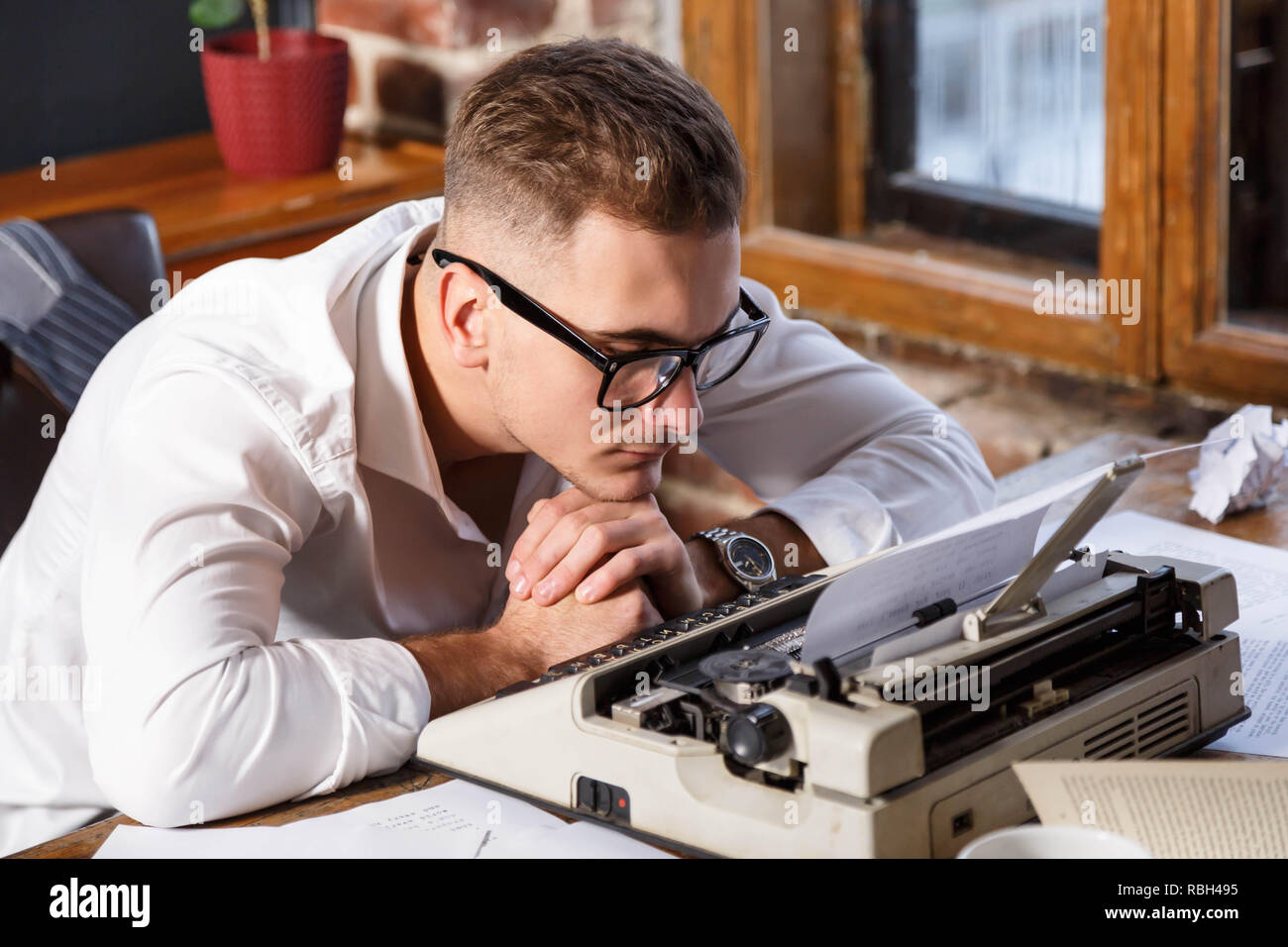 Writer at work. Handsome young writer wearing glasses and white shirt ...