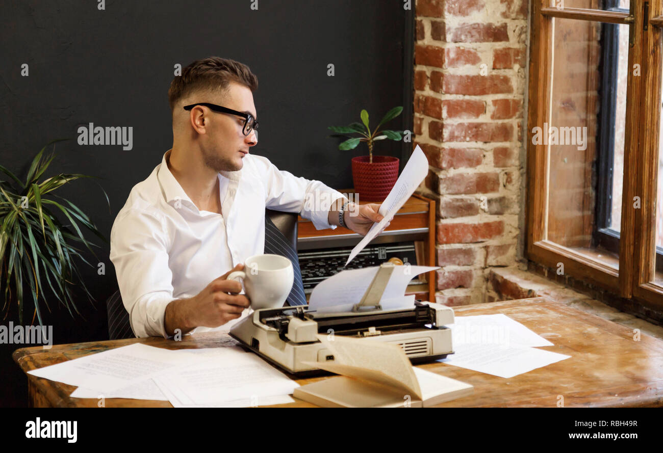 Young writer wearing glasses and white shirt reading new chapter of his ...