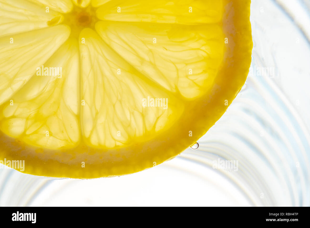 Lemon slice backlit in a glass of water close-up view Stock Photo - Alamy