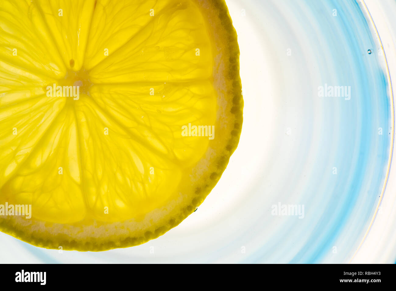 Lemon slice backlit in a glass of water close-up view Stock Photo - Alamy