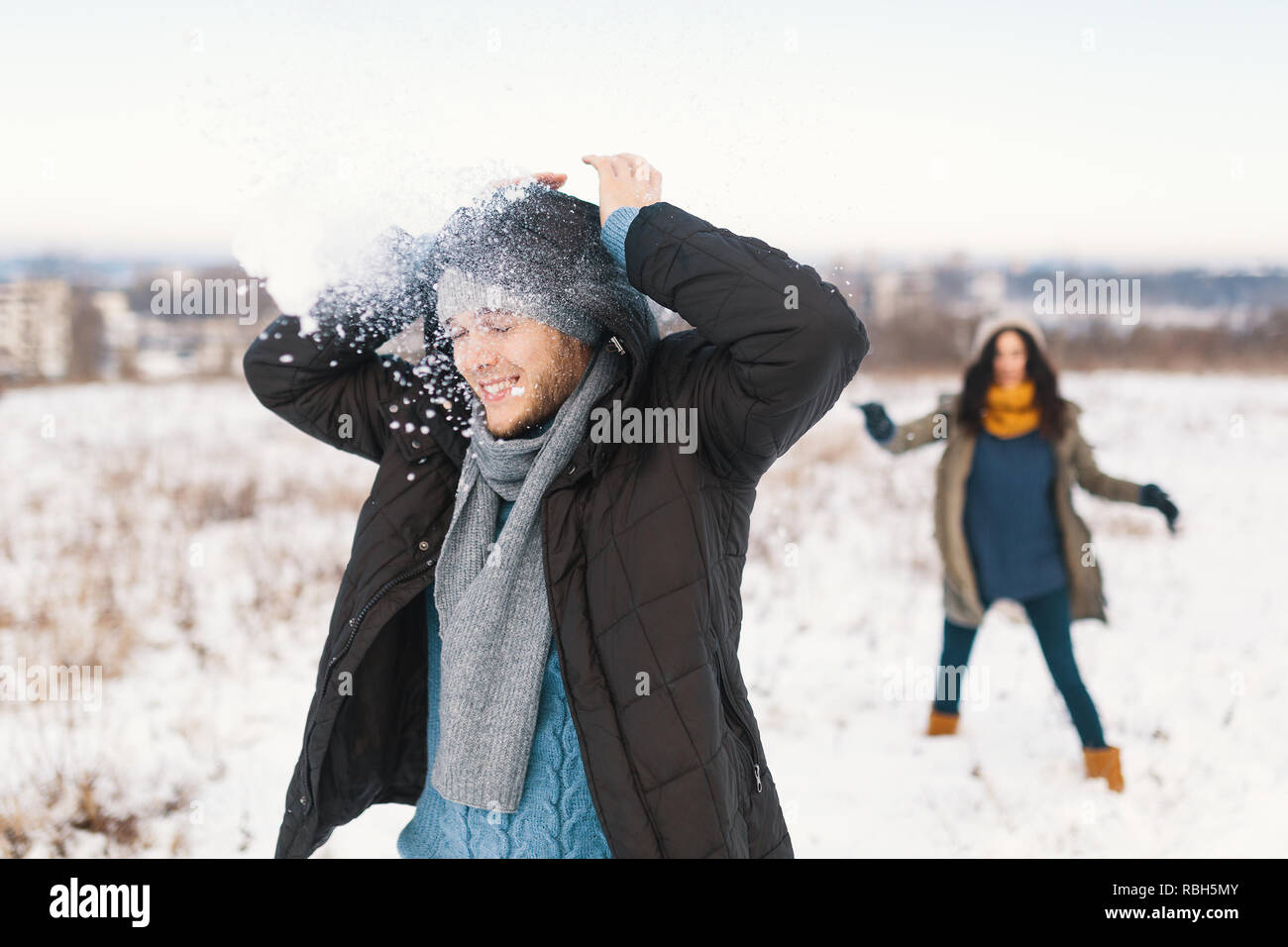 Snowball fight. Winter couple having fun playing in snow outdoors ...