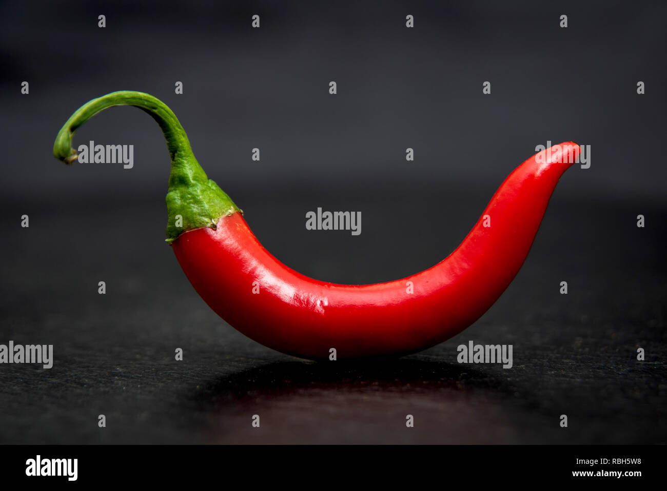 Red chili pepper on dark background. Spicy raw ingredient Stock Photo ...